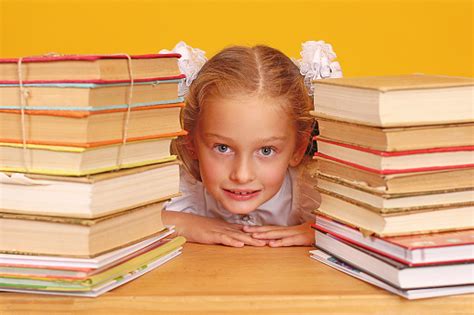 노란 배경에 교과서 더미 사이에 책상에 앉아 1 학년 소녀의 초상화 9월에 대한 스톡 사진 및 기타 이미지 9월 계획