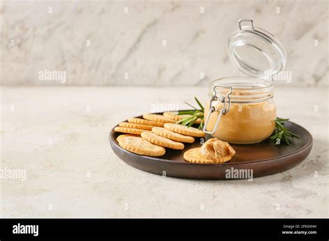 Plate With Tasty Crackers And Jar With Peanut Butter On Light