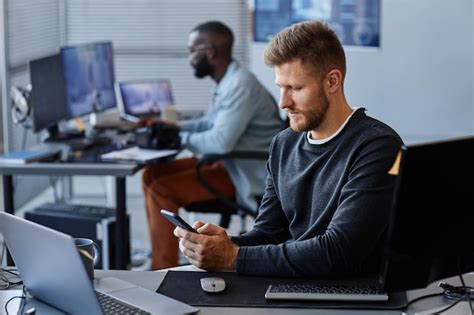 Premium Photo Side View Portrait Of Young Caucasian Man Using Smartphone At Workplace While