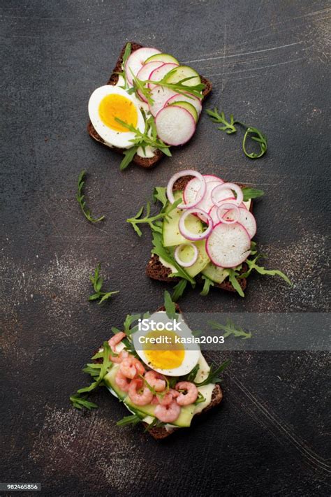 계란 새우 무 오이 크림 치즈와 Arugula 아침 오래 된 어두운 배경에 어두운 호 밀 빵에 오픈 샌드위치 덴마크의