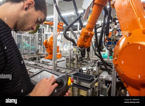 Man Programming Robot In Automotive Industrial Professional Programmer