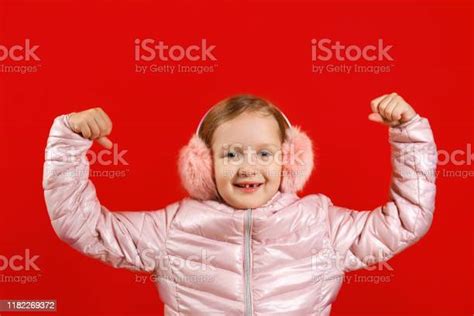 어린 소녀는 강한 손을 보여줍니다 재킷을 입은 아이와 빨간 배경에 따뜻한 귀 머프 교육 학교 성공권력페미니즘겨울의 개념 개념에 대한 스톡 사진 및 기타 이미지 Istock