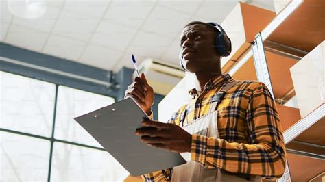 창고에서 노래하고 춤을 추는 젊은 남자가 헤드셋으로 음악을 들으며 즐거운 시간을 보내고 있다 춤 동작을 보여주는 남성 창고 직원이 상품이나 소매 제품을 즐기고 있다 핸드