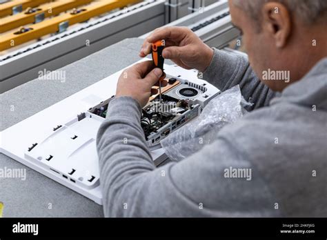 Photo Of An Adult Man In A Gray Sweater Who Assembles A Computer Monitor System Block On An