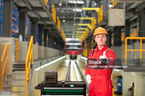 전기 열차 산업의 수리 도구를 사용하는 엔지니어의 초상화 열차 수리 공장에는 배경 이미지로 전기 열차가 있습니다 Bts