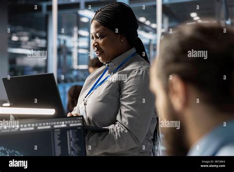 Technician Using Laptop To Oversee Server Infrastructure Powering Algorithm Training And Data