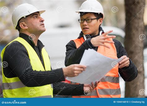 Asian Apprentice Engineer At Work On Construction Site With The Senior