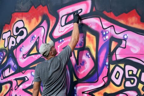 젊은 백인 남성 그래피티 아티스트가 파란색과 분홍색 톤으로 큰 거리 예술 그림을 그립니다 프리미엄 사진