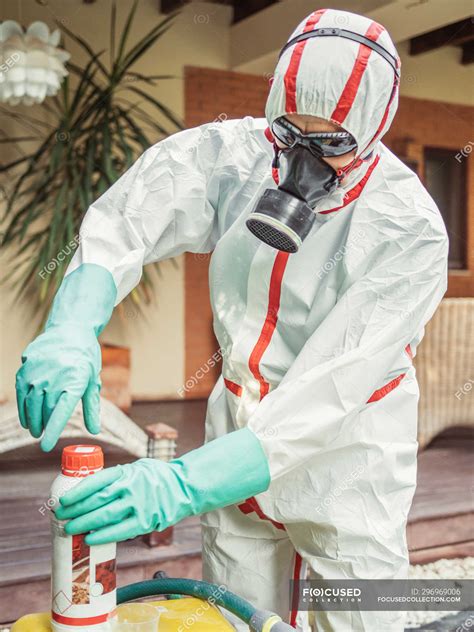 Man In Suit For Fumigation Pouring Chemical Into Tank — Extermination