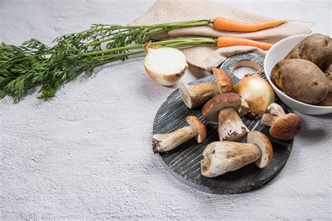 숲 포르치니 버섯을 요리하기 위한 다양한 재료는 가벼운 배경 버섯 당근 감자 양파 둥근 커팅 보드가 놓입니다 수평 배열 복사 공간을 위한 장소 0명에 대한 스톡 사진 및