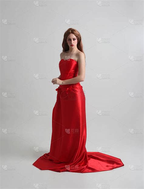 一个穿着红色长丝质长袍的女孩的全长肖像，站在灰色工作室背景的姿势