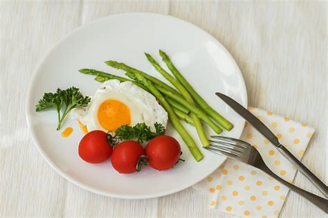 그것은 전통적인 수 제 튀김된 계란과 신선한 아스파라거스 냅킨 포크와 나이프 흰색 접시에 토마토와 함께 맛 있는 건강 한 미식 아침 식사 0명에 대한 스톡 사진 및 기타