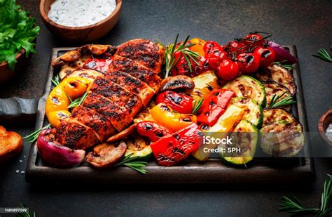 구운 야채와 치킨 필레 파프리카 호박 가지 버섯 토마토 양파 로즈마리 소박한 나무 도마 갈색 테이블 배경 평면도에 제공 가지