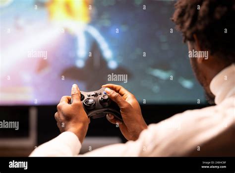 Controller Held By Gamer Sitting In Front Of Large Projector Displaying