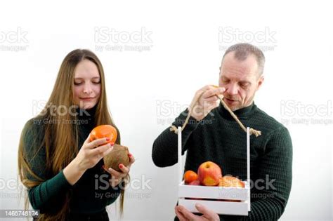 손에 과일 상자의 형태로 바구니를 들고 남자 젊은 여자는 그리드 사과와 감귤 맛있는 건강 식품 열대 국가 건강 식품 과일 가게에서 감과 코코넛 자몽을 꺼냈다 감에 대한 스톡