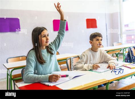 Girl Raising Hand To Answer A Question During Class In Elementary