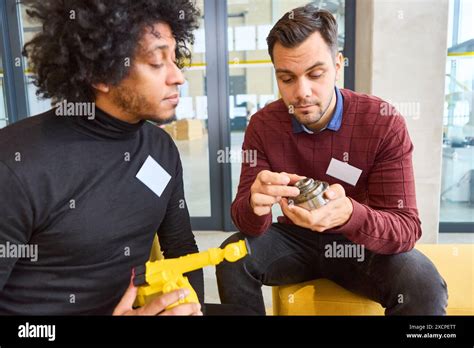 two engineers discussing robotic components closely examining parts to