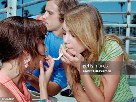 Two Teenage Girls Sit Face To Face Lighting Each Others Cigarettes High