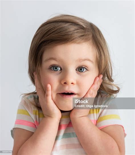 깜짝 놀란 유아 아이는 뺨에 손을 대고 파란 눈을 크게 뜨고 있었다 흰색 배경에 대한 깜짝 초상화에 아기 아이에 대한 스톡 사진 및 기타 이미지 Istock