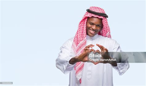 아랍 아프리카 젊은이 마음 기호와 손으로 모양을 보여주는 사랑에 웃 고 고립 된 배경 위에 전통적인 서구인을 입고 낭만적인