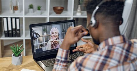 아프리카계 미국인 남자와 무슬림 여자가 집에 있는 동안 화상 통화 중에 이야기하는 뒷모습 헤드셋과 현대적인 노트북을 사용하여