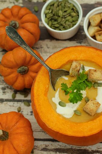 수제 호박 수프 요구르트와 파슬리 장식 금속 숟가락 호박 씨앗과 크루통 그릇 갓 수확 한 박 나무 곡물 배경 높은 전망으로