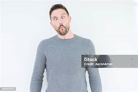 잘생긴 젊은이 격리 된 배경 만드는 물고기 얼굴 입술 고 우 스 꽝 스러운 제스처와 함께 캐주얼 스웨터를 입고 재미 있는