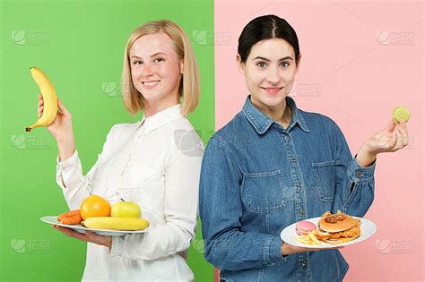 饮食。节食的概念。健康食品。美丽的年轻女人在水果和不健康的快餐之间选择