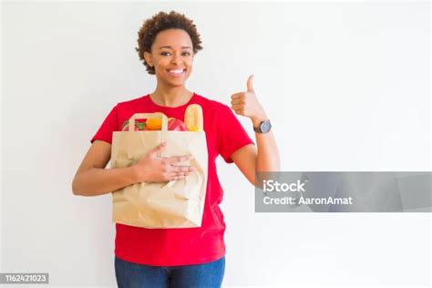 젊은 아프리카 계 미국인 여자 들고 종이 가방 의 전체 신선한 식료품 행복 와 큰 미소 하 고 확인 기호 엄지 손가락 우수한 기호 가방에 대한 스톡 사진 및 기타 이미지
