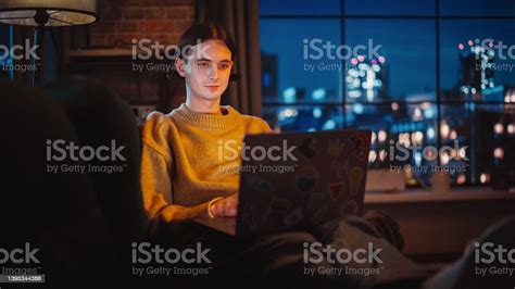 저녁에는 세련된 로프트 아파트의 노트북 컴퓨터에서 집에서 일하는 잘 생긴 남자 창조적 인 사람 소셜 미디어를 확인 인터넷 검색 큰 창문에서 도시 도시보기 Lgbtqia