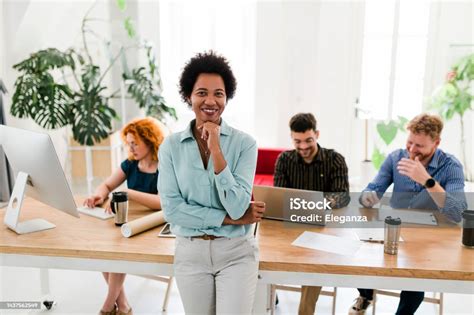 자신감 넘치는 중년 사업가가 배경에 동료들과 함께 회의실에서 카메라에 미소 지으며 서 있습니다 경영자에 대한 스톡 사진 및 기타 이미지 Istock