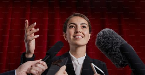 기자와 인터뷰를 하고 붉은 커튼에 대고 마이크에 대고 말하는 웃는 여성 공무원의 허리 위 초상화 사진 Unsplash의 정치 이미지