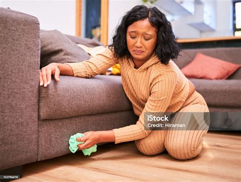 슬픈 여자는 집 바닥에 앉아있는 거실에서 천으로 소파를 청소합니다 불행하거나 혐오감이나 울고있는 얼굴을 가진 주부가 현대 집의 라운지에서 소파를 소독합니다 소파에 대한 스톡