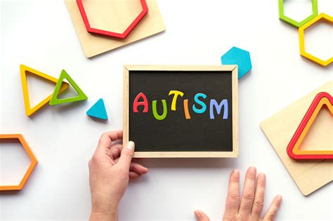 텍스트 자폐증 무지개 색상의 칠판에 단어 다양한 대담한 색상의 나무 삼각형과 육각형을 중첩 인간의 손에 분필 보드 감각 지각에