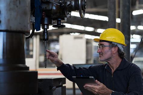 산업 공장에서 선반 기계의 부품 품질을 검사하고 안전 유니폼 헬멧을 착용한 수석 남성 엔지니어 작업자 성숙한 남성 기술자 작업자