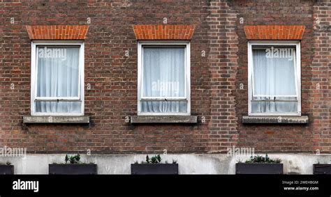 Three Aligned Classic White Windows Of Typical London Architecture With Red Brick Wall Stock