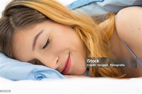 여자는 일어나 고 유쾌 하 게 웃는 다 그녀는 침대에 누워 하 고 푸른 옷을 입은 게으름 행복의 감정입니다 휴식과 평온의