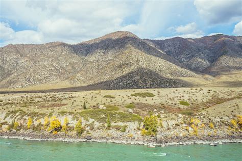 햇살이 내리쬐는 넓은 청록색 산강을 따라 나무에 황금잎이 있는 다채로운 가을 풍경 가을에는 금색의 큰 산강과 노란 나무가 있는 밝은 알프스 풍경 가을에 대한 스톡 사진 및