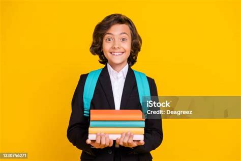 사진 긍정적 인 재미있는 작은 여학생 홀드 더미 책 착용 배낭 검은 색 유니폼 고립 된 노란색 색상 배경 갈색 머리에 대한 스톡 사진 및 기타 이미지 Istock