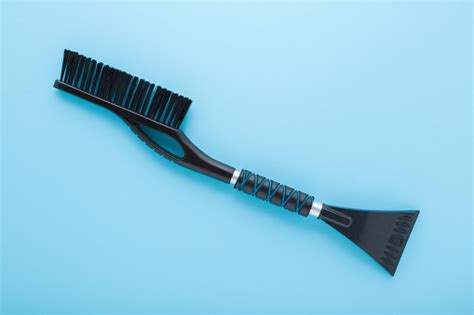 밝은 파란색 테이블 배경에 눈과 얼음 청소를 위한 스크레이퍼가 있는 새로운 진한 검은색 자동차 브러시 파스텔 색상 근접 촬영