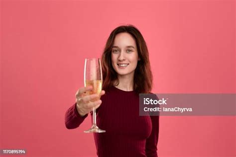 흥분 예쁜 갈색 머리 소녀 는 어두운 분홍색 배경에 고립 된 서 있는 반짝이는 샴페인의 와인 잔을 들고 카메라에 미소 축하의 개념 갈색 머리에 대한 스톡 사진 및 기타