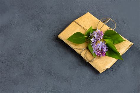 스프링 조성물 갈색 공예 종이로 포장하고 어두운 배경에 라일락의 무리로 장식 된 예쁜 선물 상자 맨 위 보기 텍스트에 대 한 공간을 복사 합니다 공예에 대한 스톡 사진 및