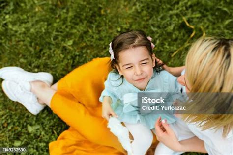 야외에서 함께 시간을 즐기고 그녀의 어머니와 함께 노는 행복 한 아이의 위에서 보기 그녀의 엄마와 함께 솜 사탕을 먹는 쾌활 한 어린 소녀 공원의 녹색 잔디에 앉아 어머니의