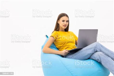 젊은 여성은 신생 고객과 그녀의 컴퓨터 채팅에서 작업 큰 가방 라운지 의자는 흰색 색상 배경에 고립 된 캐주얼 스타일의 옷을 입고 앉아 가방에 대한 스톡 사진 및 기타