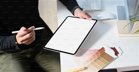 젊은 남성 그래픽 디자이너의 자른 샷은 워크 스테이션에서 대화 형 펜과 빈 화면 디지털 태블릿으로 작업하고 있습니다 사진