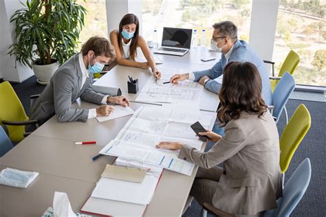 컨퍼런스 테이블에서 열린 회의에서 보호얼굴 마스크를 착용한 4명의 비즈니스 인원이 차트를 분석합니다 30 34세에 대한 스톡 사진 및 기타 이미지 Istock