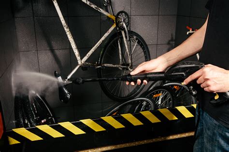 워크샵에서 자전거의 서비스 전문 세척 근접 한 손 젊은 백인 세련 된 남자 자전거 청소 자동 전기 워터 펌프를 사용 하 여 스프레이는 압력에서 산란 개념에 대한 스톡 사진