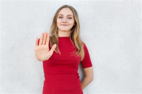 그녀의 손으로 빨간 드레스 만들기 중지 제스처를 입은 젊은 여자의 초상화 그녀의 거부 및 금지 손바닥을 보여주는 흰색 배경 금발 여성 서의 고립 된 초상화를 자른 Red