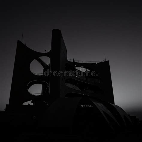 silhouette of a modern architectural structure against a dark sky the