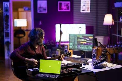 Sound Engineer Playing Guitar Next To Laptop Showing Greenscreen